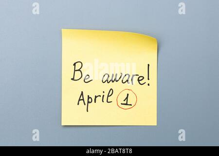 be aware on yellow sticky note over a grey background. april fools day ...
