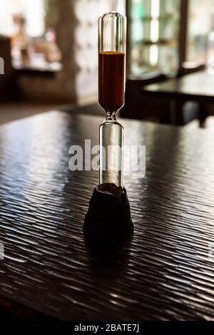 Hourglass on the table in caffe on wooden working table with morning ...