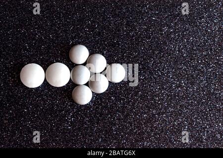 White pills, tablets capsule form a triangle in a circle on a dark ...