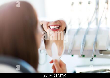 Young female dentist with dental mirror and tooth model on blue ...