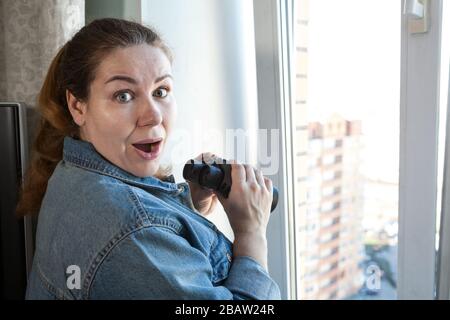 shocked adult woman spying out the window with binoculars Stock Photo ...
