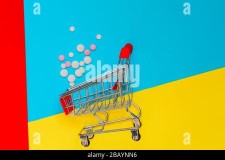 Overturned shopping cart with pills on color background Stock Photo - Alamy