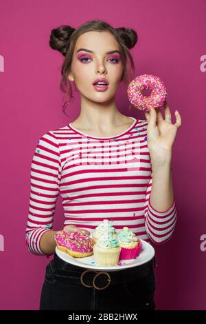Beautiful model with sweets at pink background Stock Photo - Alamy