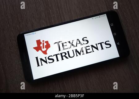 Texas Instruments logo displayed on a smartphone with tech items on a ...