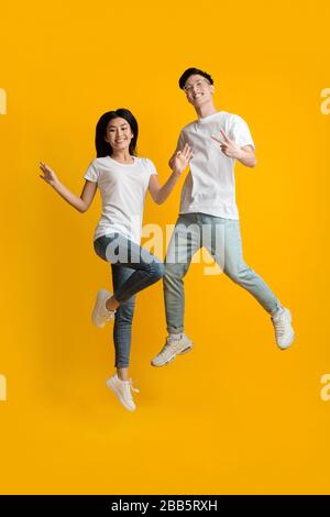 A cheerful and excited young Asian couple is enjoying popcorn while ...