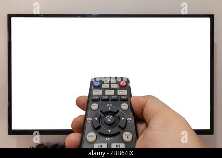 Person pointing a TV remote and pressing buttons in front of a TV with ...