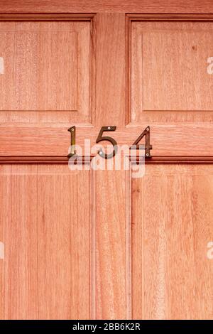 House number 154 on a light natural wooden front door Stock Photo - Alamy