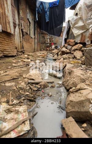 Open sewer running through small alley with metal slum shacks either ...
