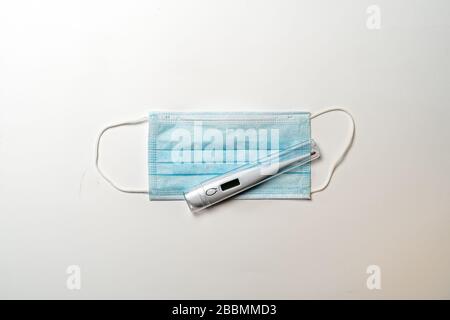 Typical white 3-ply surgical mask with rubber earhooks to cover mouth ...