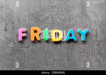 Friday word written with colorful letters on white marble stone ...