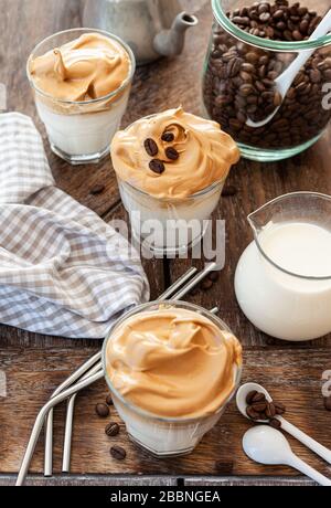 Delicious coffee with milk in glass and beans on brown background ...