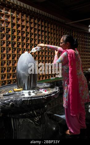 Hindu woman pouring milk over a Shiva lingam. Neelkanth Mahadev Temple ...