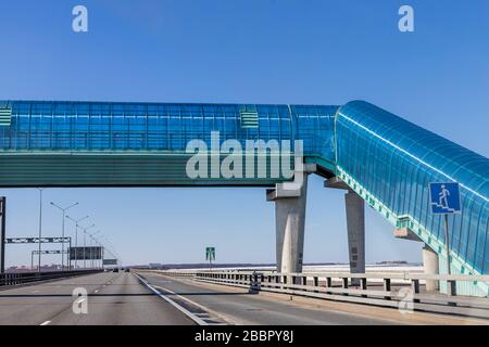 A pedestrian overpass across a busy city highway provides access from a ...