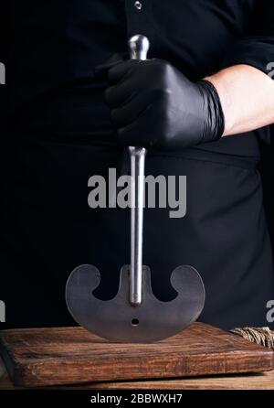 A man in gloves holds an ax in his hands against a black background ...