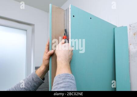 Construction worker cutting gypsum drywall by using electric cutter ...