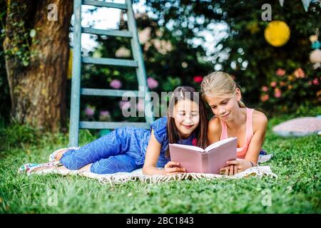Happy friends reading a book together under a tree at the park Stock ...