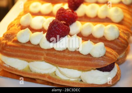 French traditional eclair, decorated with raspberry and cream on the ...