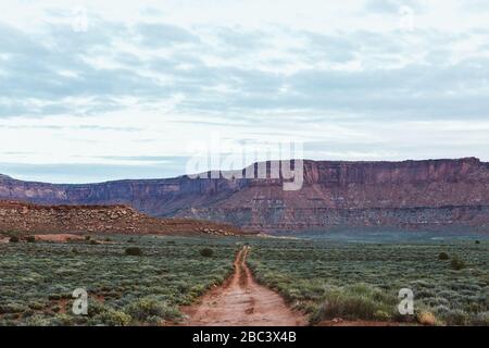 double track dirt road in the desert beneath red rock buttes of utah ...