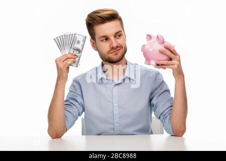 Man putting money into piggy bank Stock Photo - Alamy