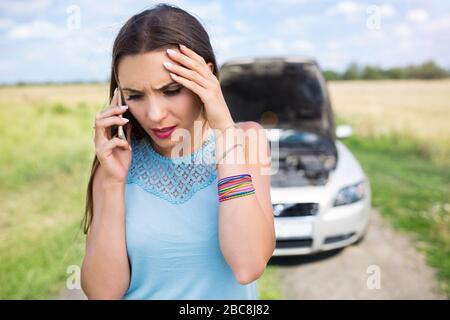 Young woman holding broken smartphone showing cracked screen looking ...