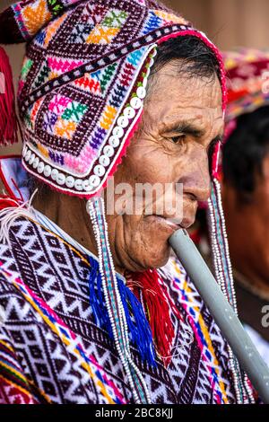Indigenous musician playing a flute wearing a traditional costume as ...