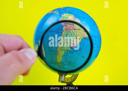 selective focus of man holding magnifying glass near coins on plaid ...