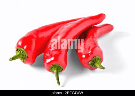 three red peppers of an elongated shape on a white background with ...