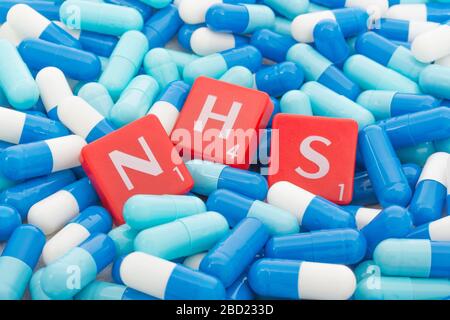 NHS letters tiles sinking into pills. For NHS overwhelmed by Covid 19 ...