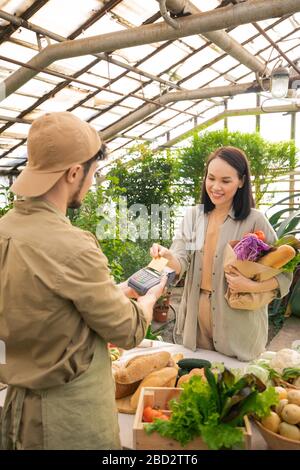 Grocery store customer holding contactless card near card reader to pay ...