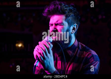 Man with enthusiastic face holds microphone, singing song Stock Photo ...