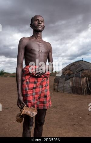 A male member of the Dassanetch ethnic group or tribe poses holding his ...