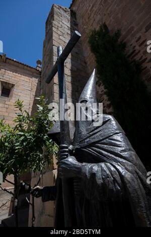 Statue of a penitent (Nazareno) in a pointed hood (capirote) carrying a ...