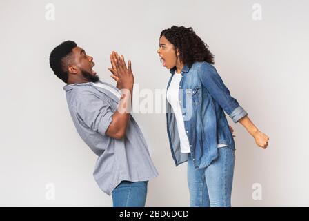 PMS Concept. Mad african american woman yelling at her scared boyfriend ...
