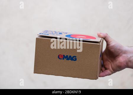 Deliveryman holding eMAG cardboard box isolated on blurred background ...