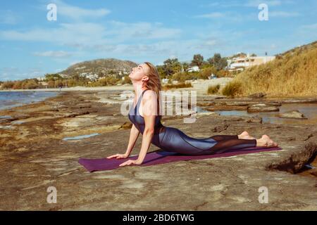 Young plastic woman doing sports exercises on the beach Stock Photo - Alamy
