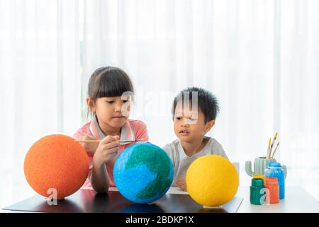 Asian elementary schoolboy painting the moon in science class learning ...
