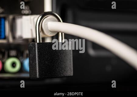 Closed lock hanging on a network cable plugged into a computer. The ...