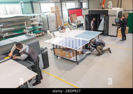 Worker printmaker technician operator works in large digital printing ...