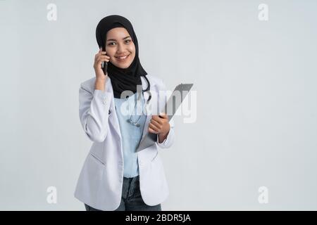 Asian female doctor talk phone call consult patient holding clipboard ...