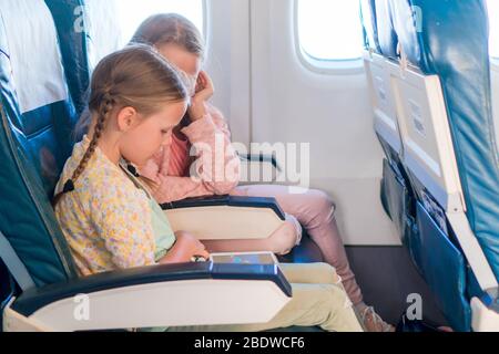 Adorable little girls traveling by an airplane. Children sitting by ...