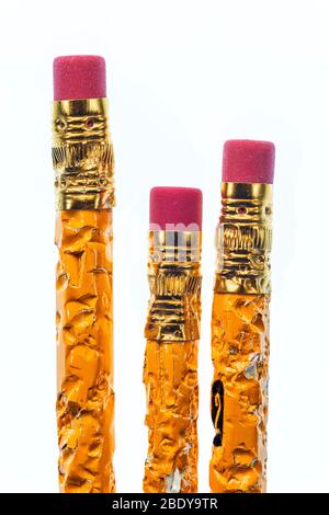 Vertical shot of the eraser end of three chewed pencils on a white ...