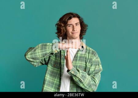 Expressing refusal. Handsome teenager gesturing TIME OUT on turquoise ...