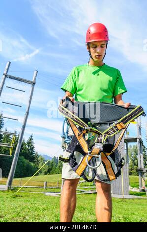 Preparing for climbing exercises in high ropes park with an instructor ...
