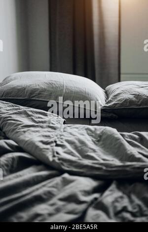 Messy bed with crumpled blankets in a bedroom setting Stock Photo - Alamy