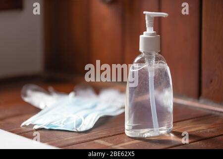 A closeup of a bottle of hand sanitizer and face masks, concept of stay ...