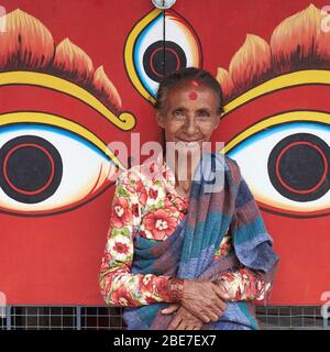 A Nepalese woman at a Hindu shrine, a red tika mark on her forehead ...