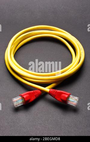 Twisted yellow cable with LAN or Ethernet connectors on a white ...