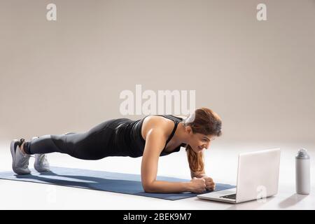 Woman planking while looking at the laptop in front of her Stock Photo ...