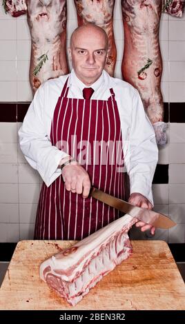 In this image, a butcher is showing a pork loin to a customer, ready to ...