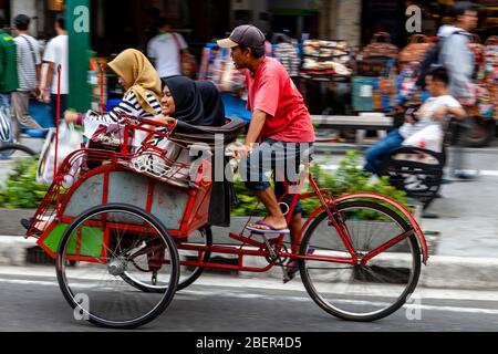 Muslim women travel by rickshaw in crowded street scene in city of ...